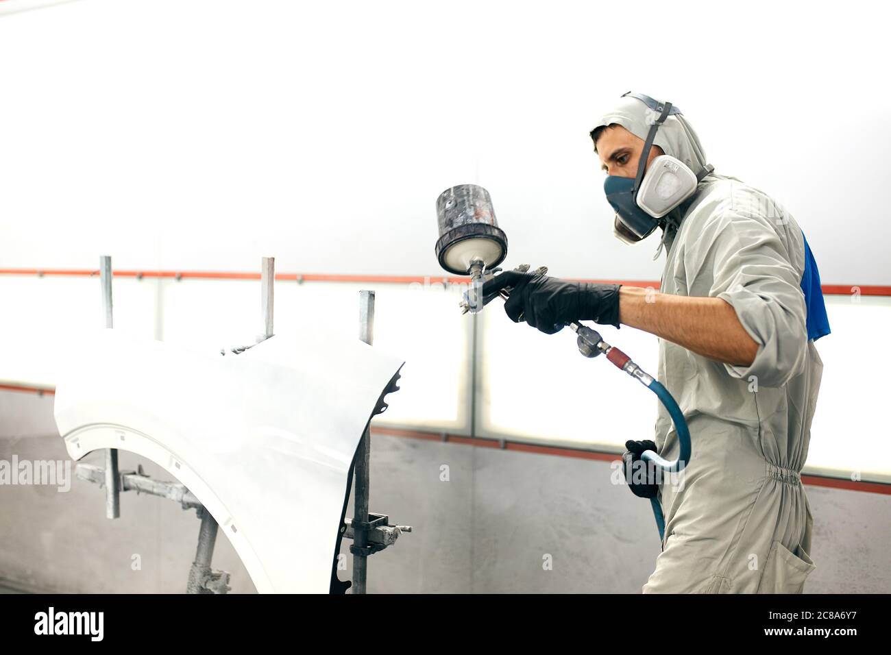 mechanic worker painting car part at automobile repair service station ...