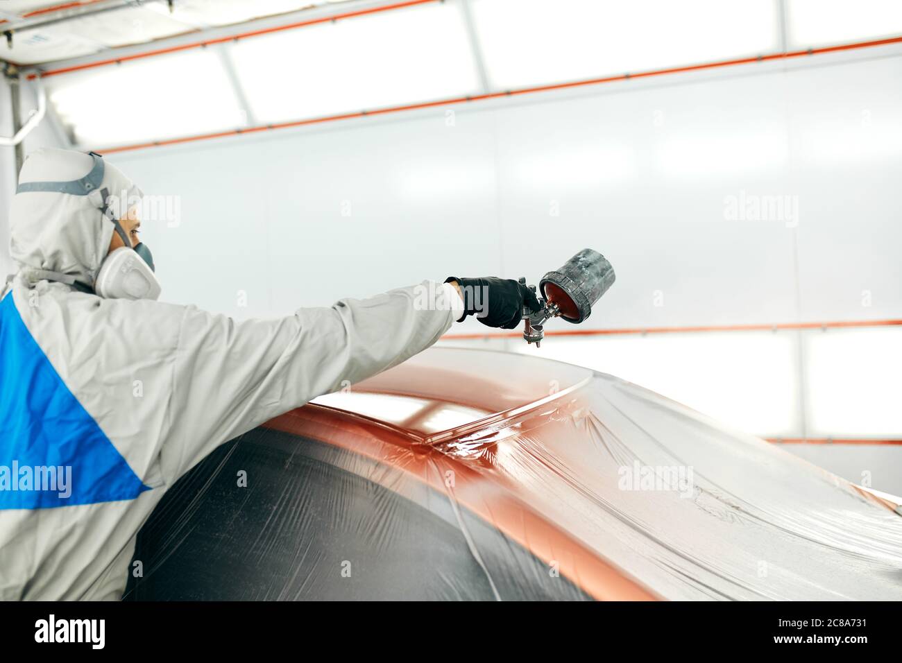 Car body painter spraying paint in garage or workshop with airbrush ...