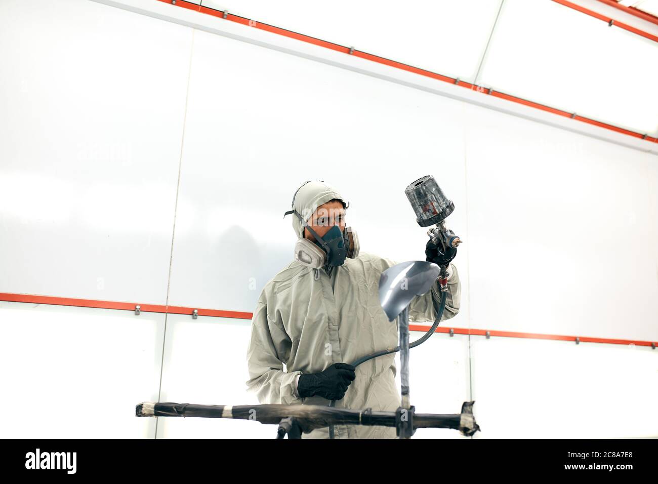 Man with protective clothes and mask painting car roof using compressor ...