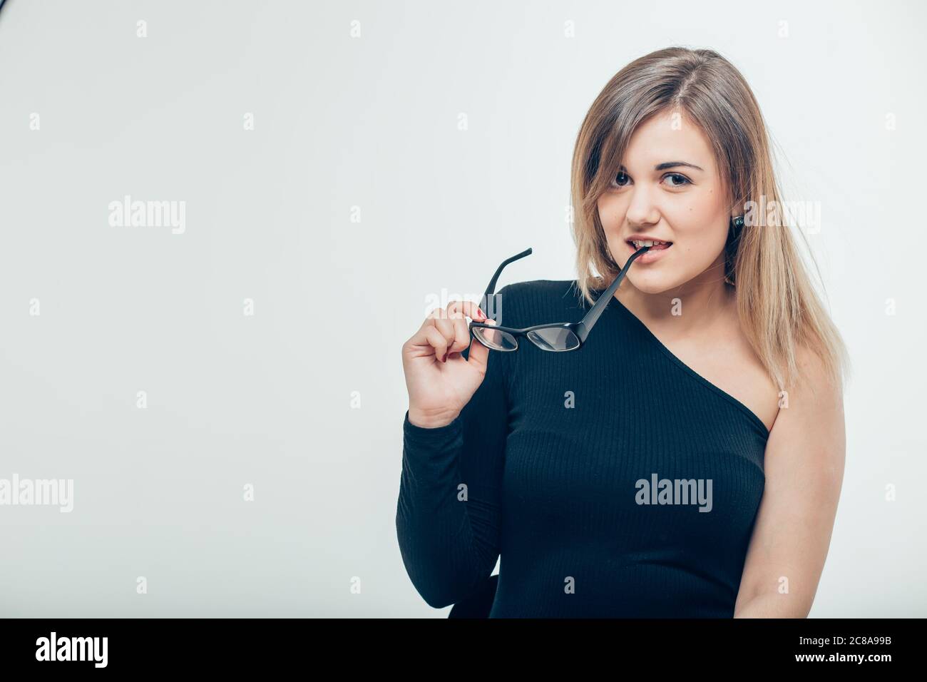 Pretty beautiful woman biting glasses in studio Stock Photo - Alamy