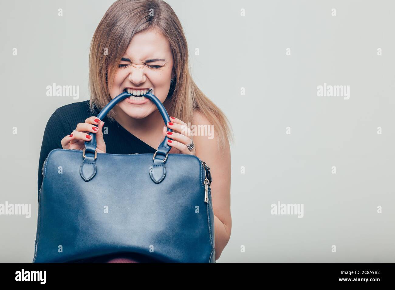 Woman bite her leather bag. shopping concept Stock Photo - Alamy