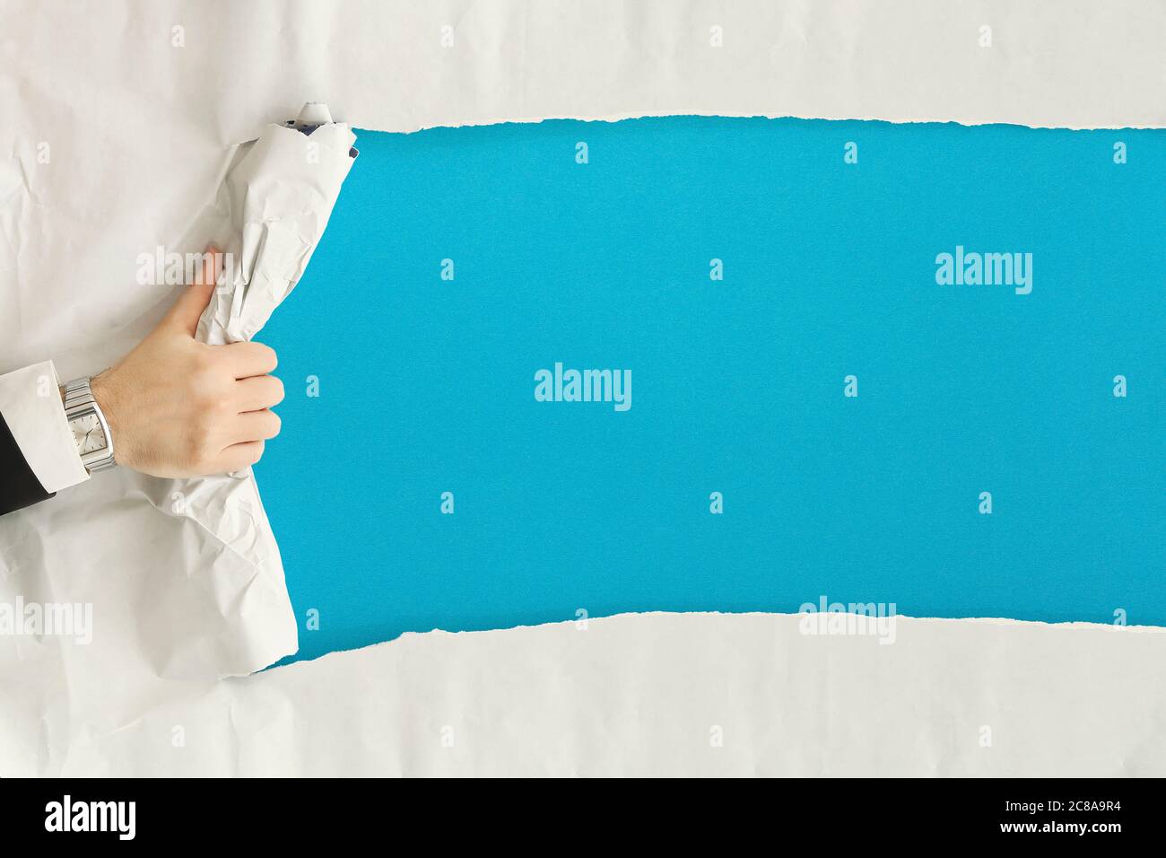 male hand ripping a paper sheet revealing a blank blue surface Stock ...