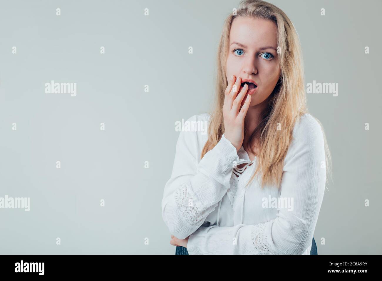 Surprised young woman shouting over grey background. Looking at camera ...