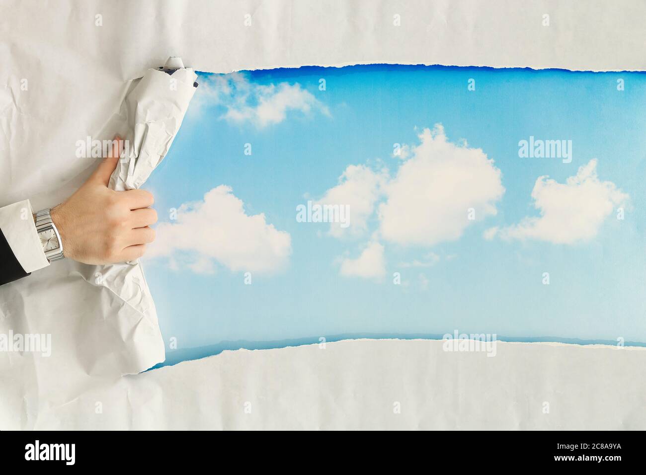 male hand ripping a paper sheet revealing a bright sky Stock Photo - Alamy