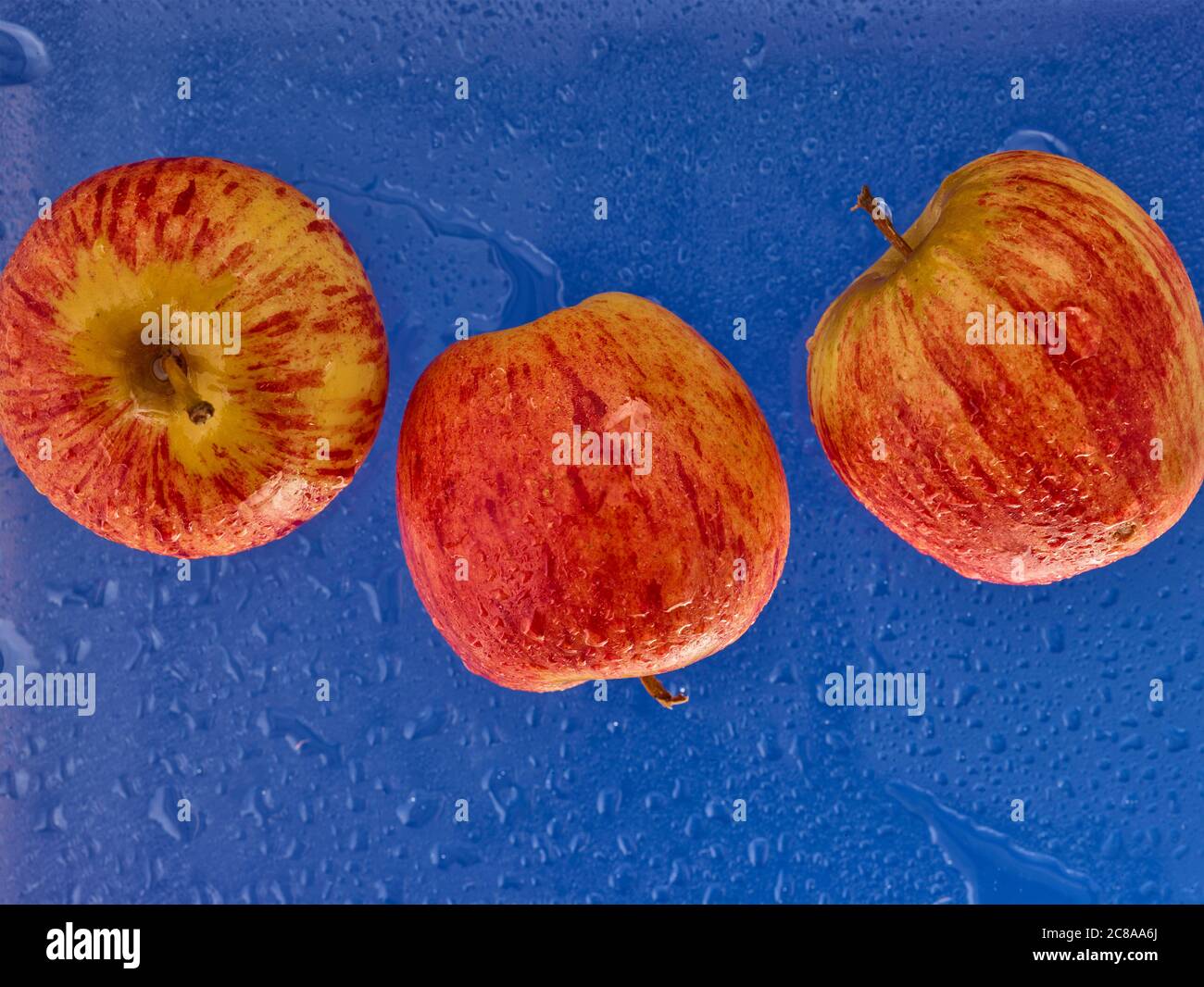 Red eating apple and water droplets on plain coloured background, food ...