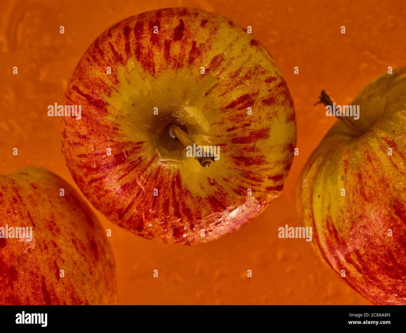 Red eating apple and water droplets on plain coloured background, food ...