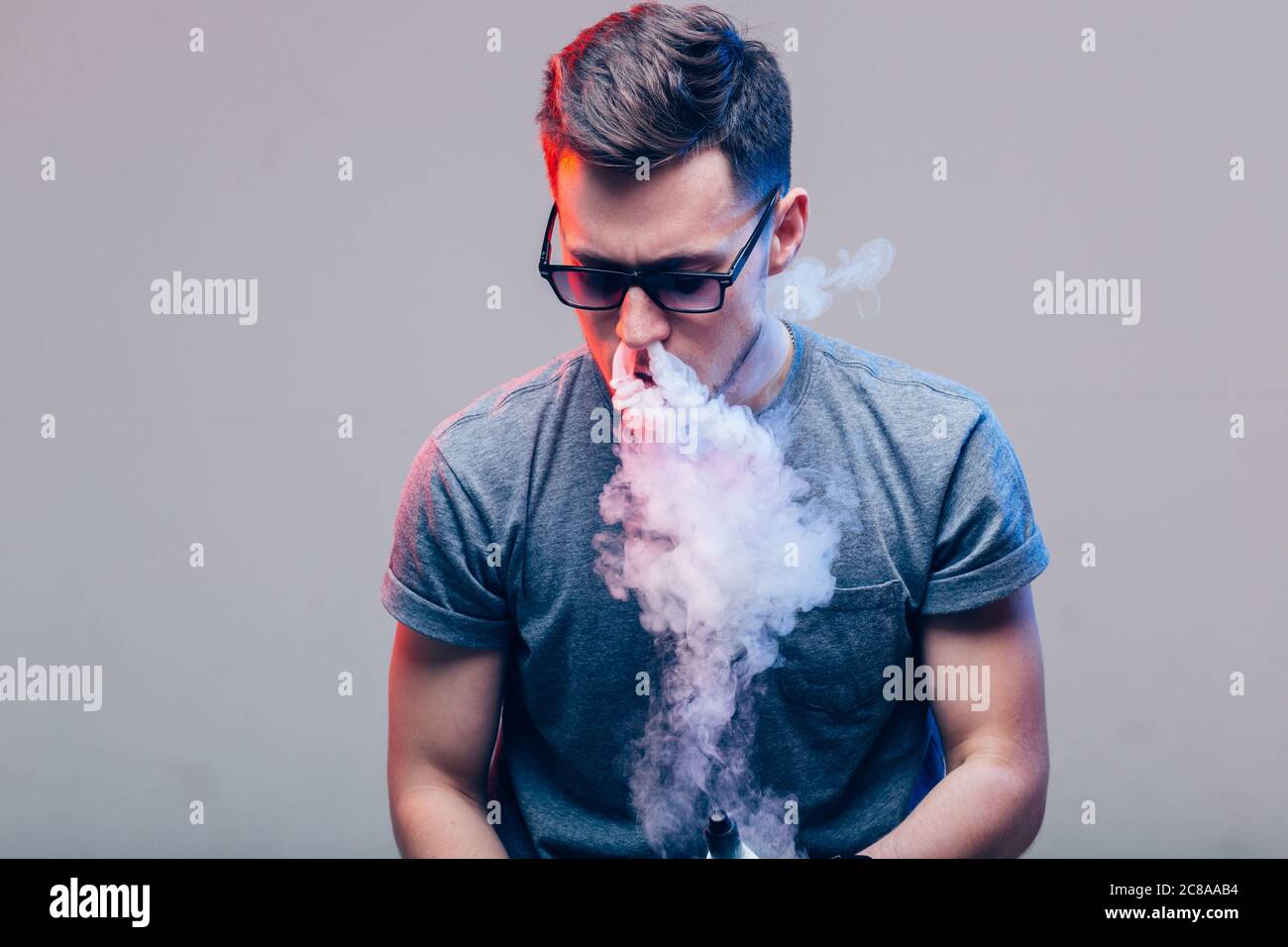 Men with beard in sunglasses vaping and releases a cloud of vapor in ...