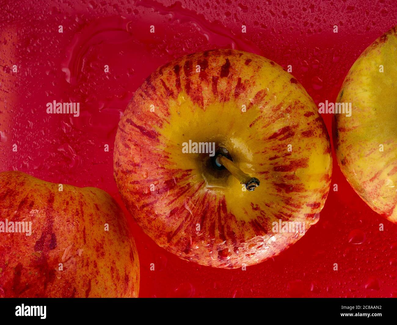 Red eating apple and water droplets on plain coloured background, food ...