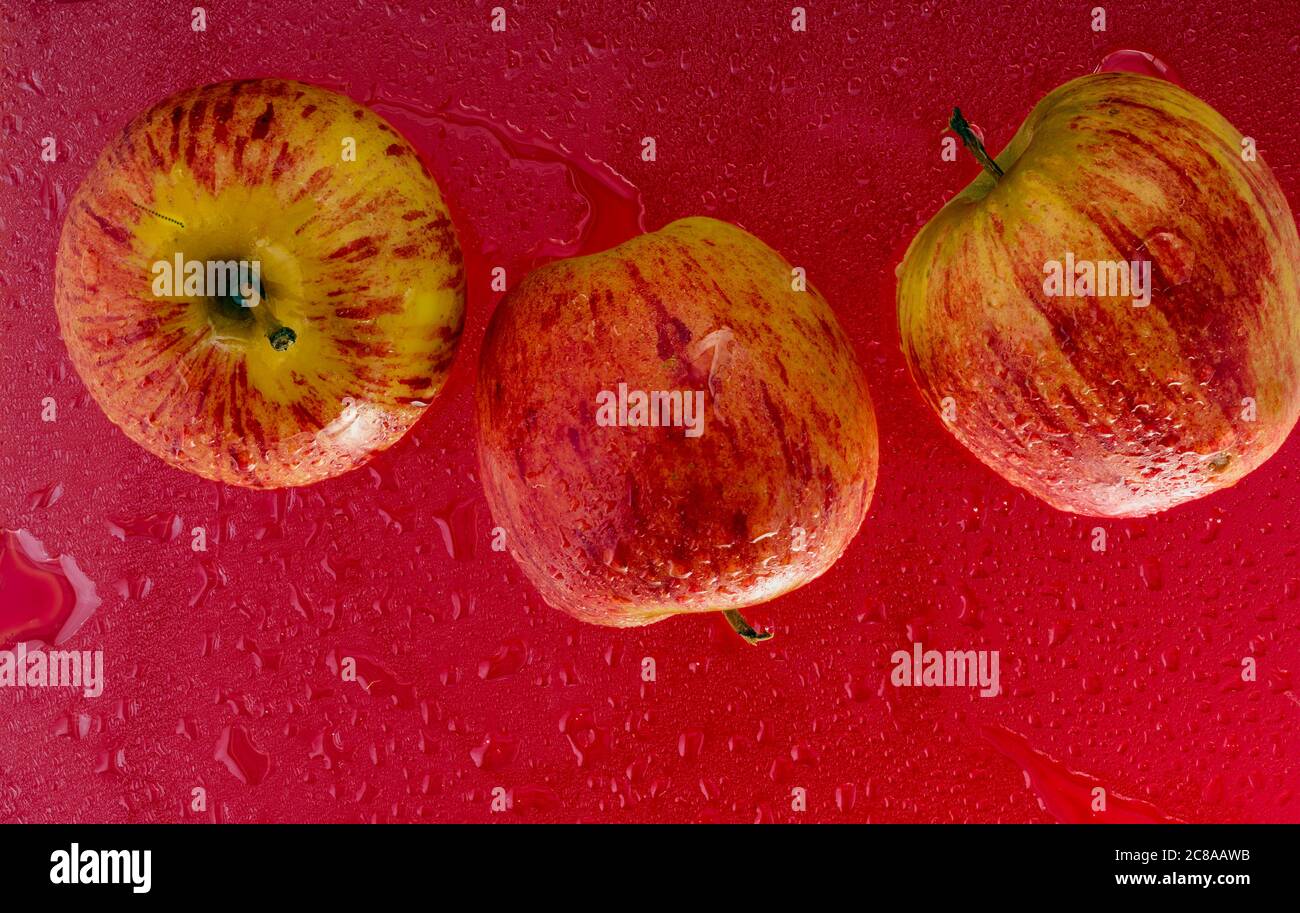 Red eating apple and water droplets on plain coloured background, food ...