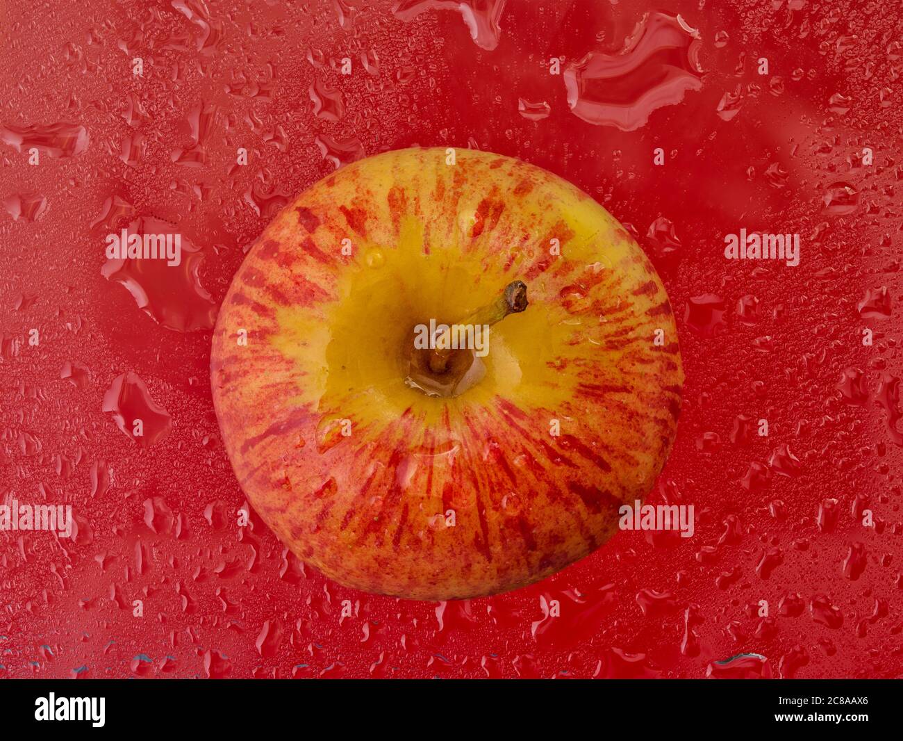 Red eating apple and water droplets on plain coloured background, food ...