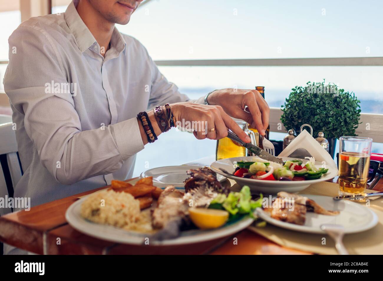 Man eats fish with vegetables in outdoors restaurant. Fresh seafood ...