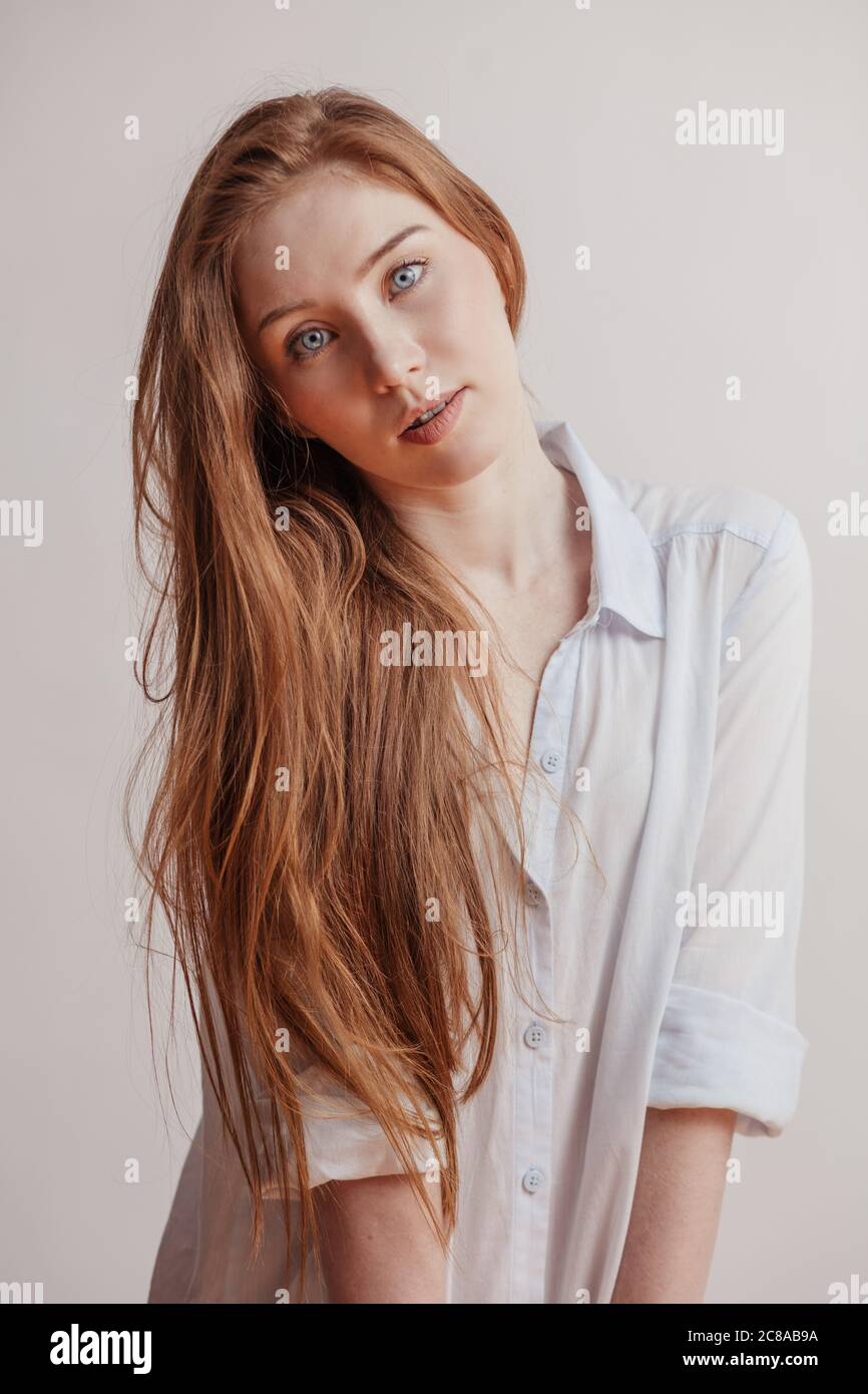 Portrait of young woman with long loose red hair, looking at camera ...