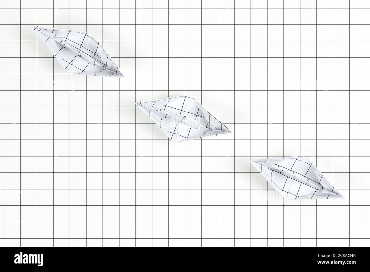 top view of three paper boats on white paper surface with squares Stock ...