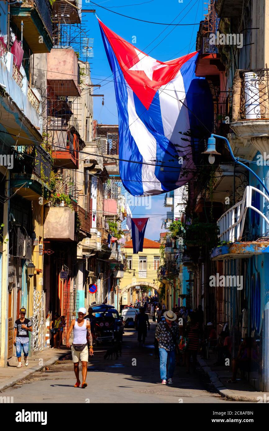 Urban scene with cuban flags, people and aged buildings in Old Havana ...
