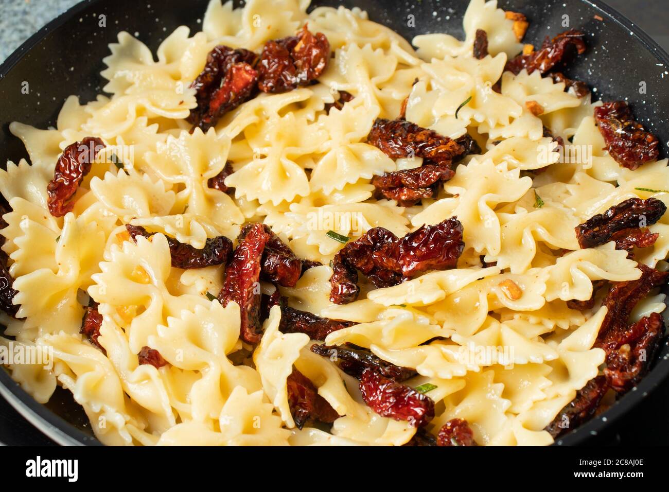 Pan-fried pasta with sun-dried tomatoes and garlic. Stages of cooking ...