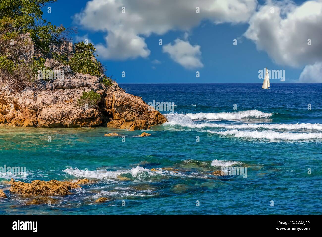 Surf Hitting Rocks with Sailboat Stock Photo - Alamy