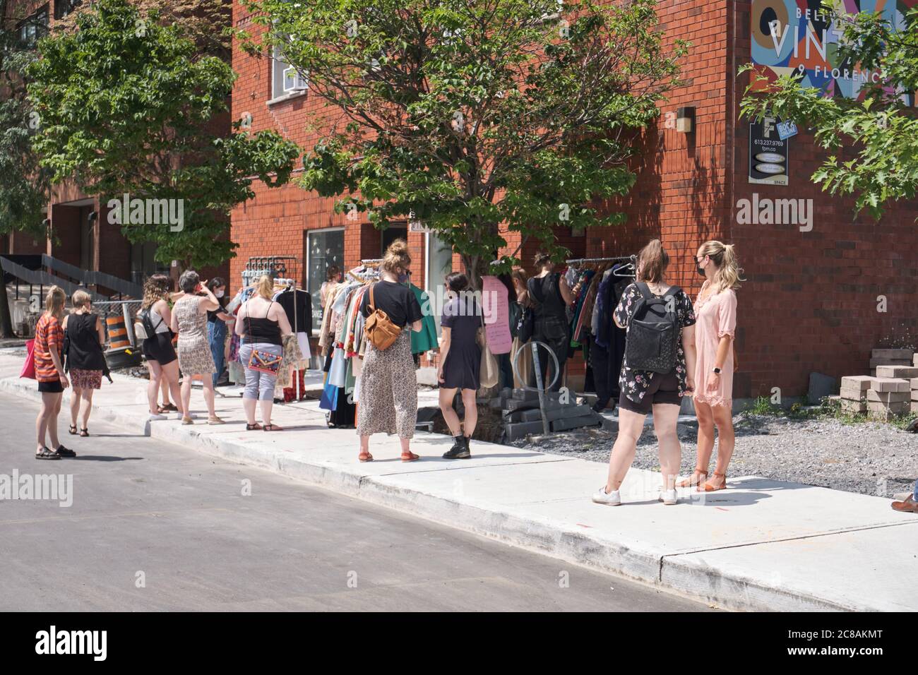 People lined up around clothing rack display outdoors of Vintage shop ...