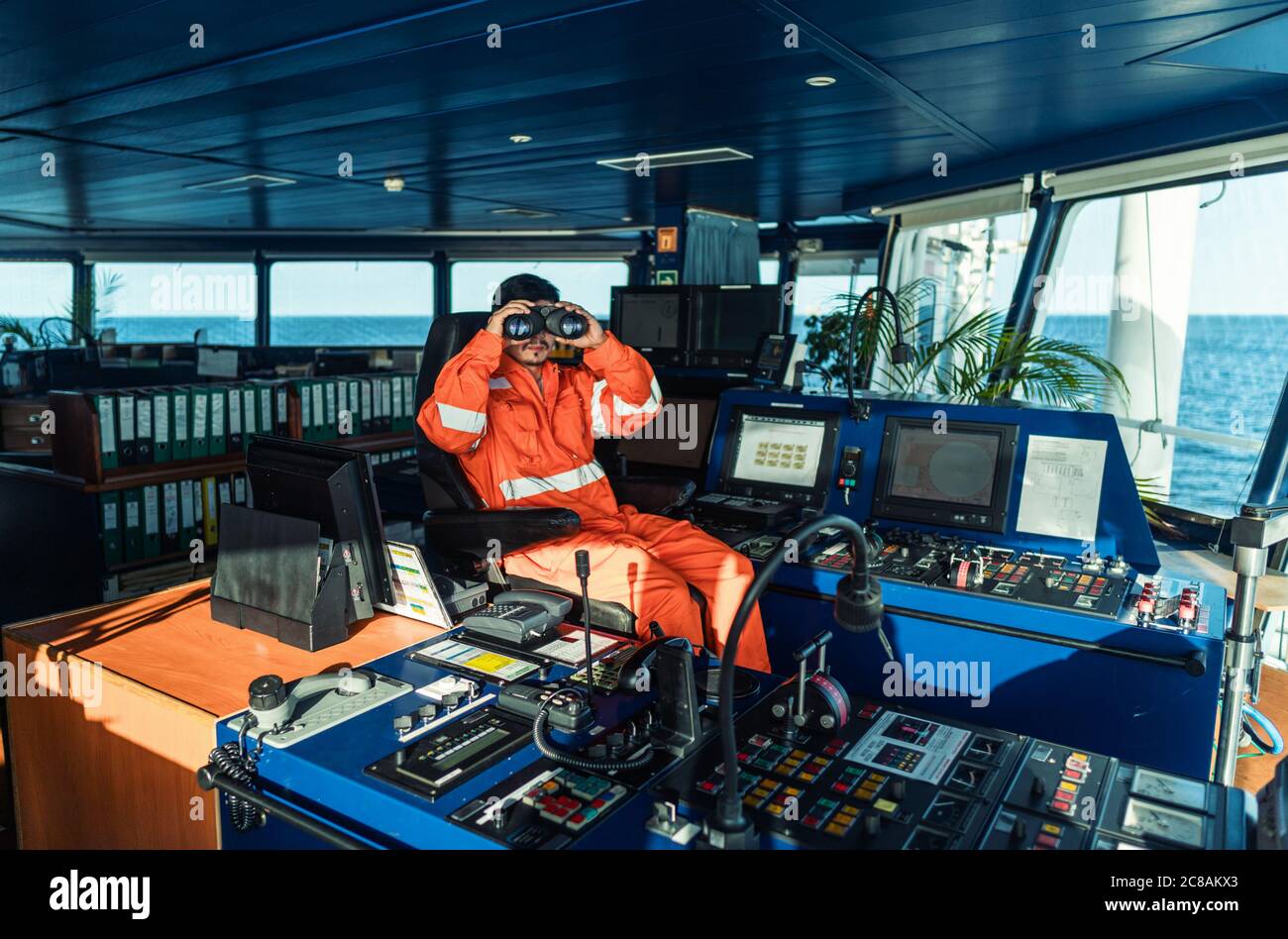Filipino deck Officer on bridge of vessel or ship looking through ...