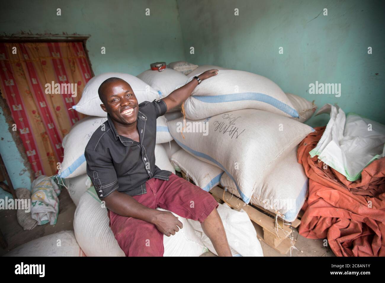 Peter Kasende (21) rests from lifting sacks of maize at a bulking ...