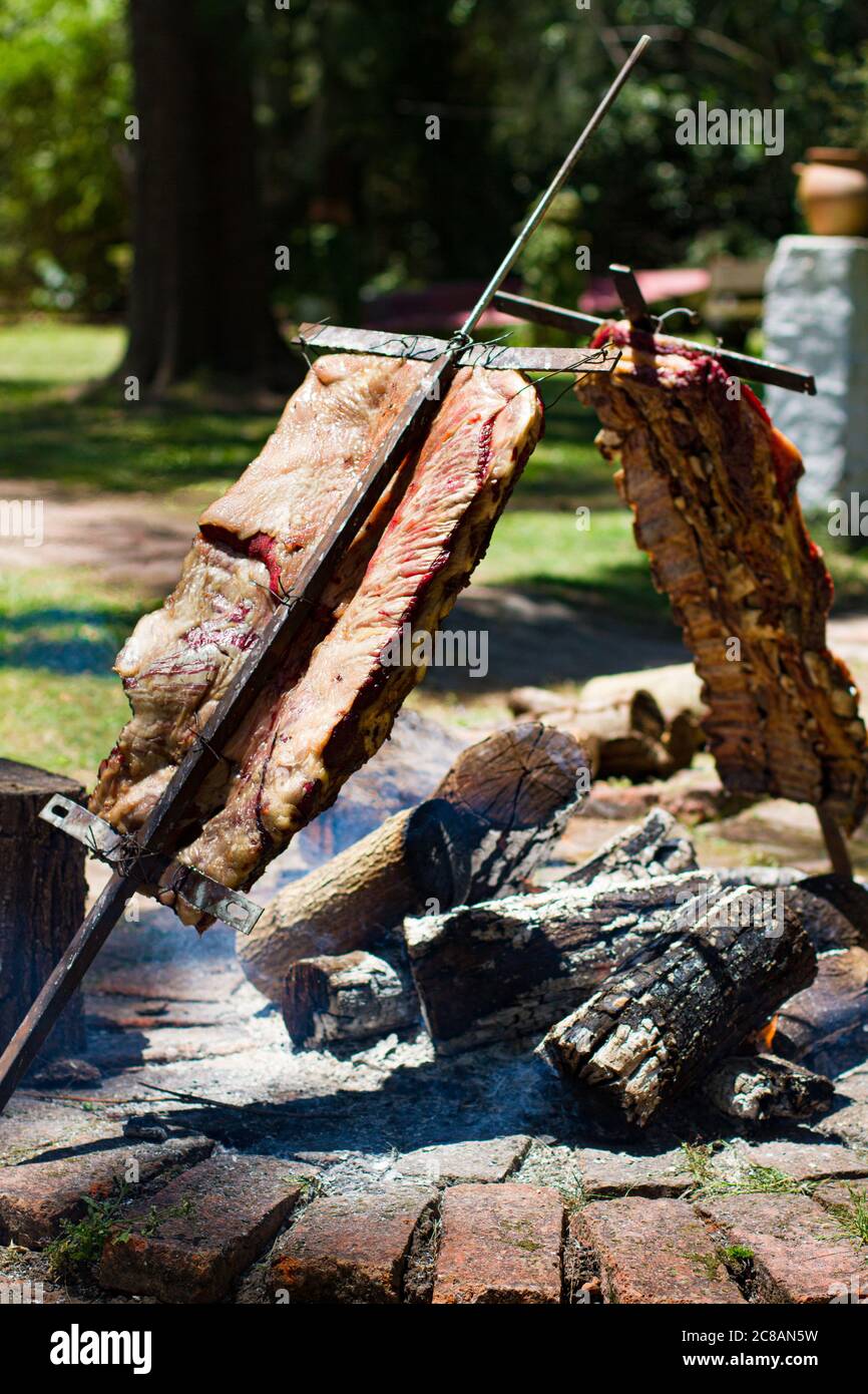 Asado, traditional barbecue dish in Argentina, roasted meat cooked on a crossed vertical grills ...