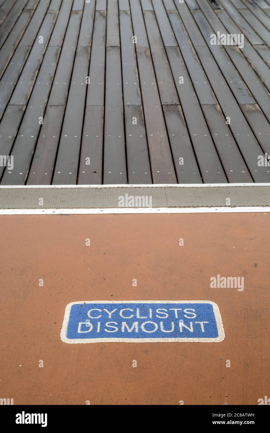 Cyclists dismount sign painted on footpath Stock Photo - Alamy