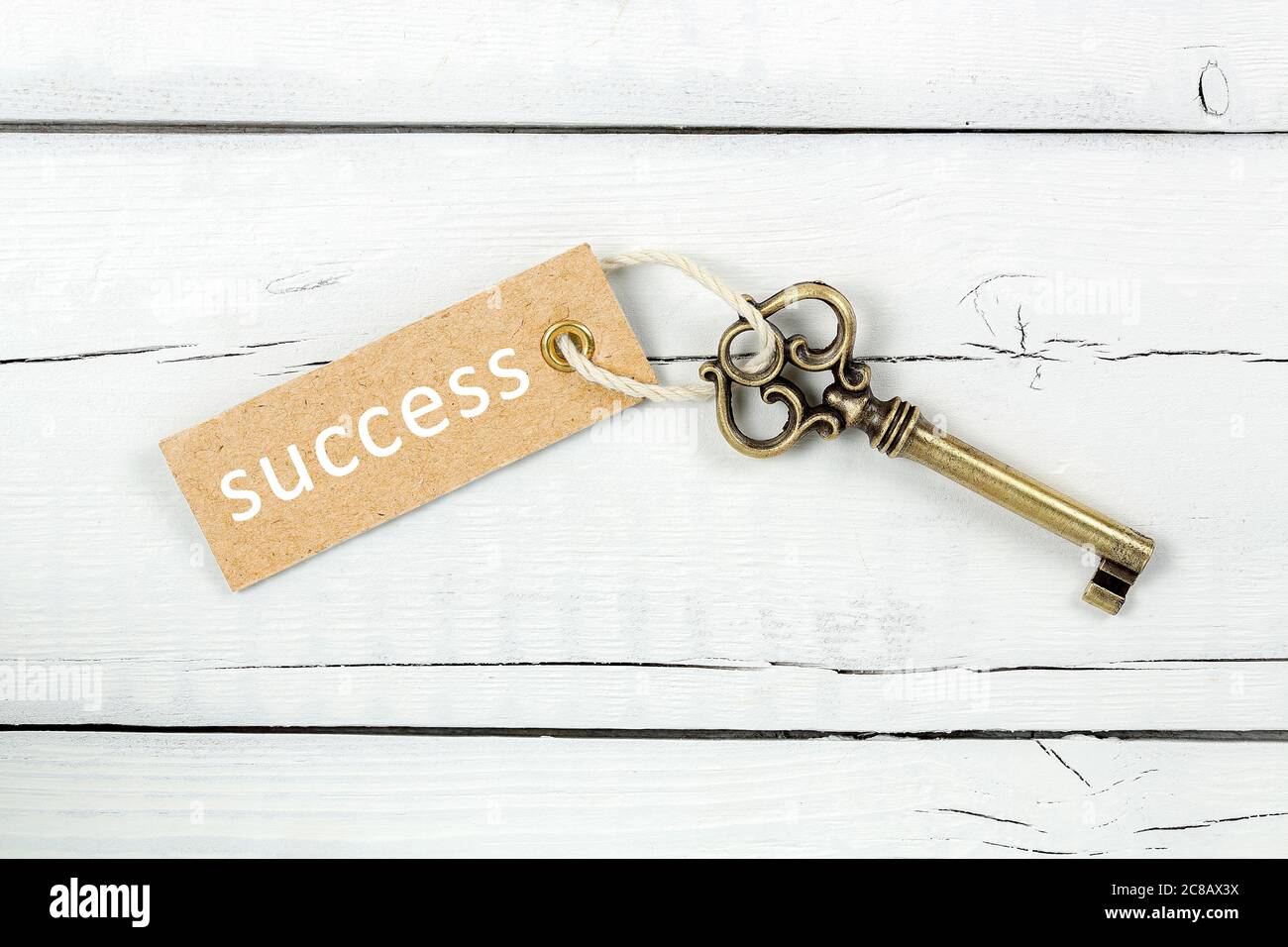 antique key with tag on white planks, success concept Stock Photo - Alamy