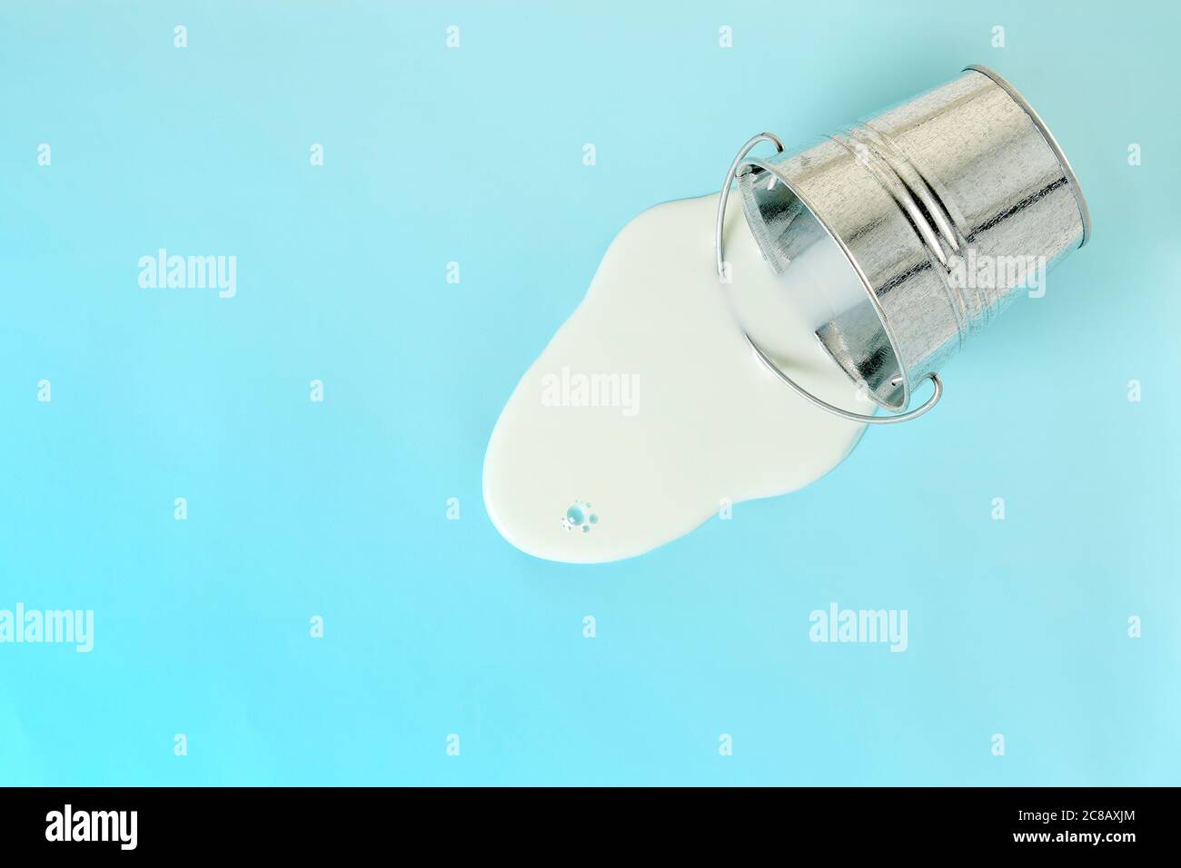 bucket with spilt milk on blue surface with copy space Stock Photo - Alamy