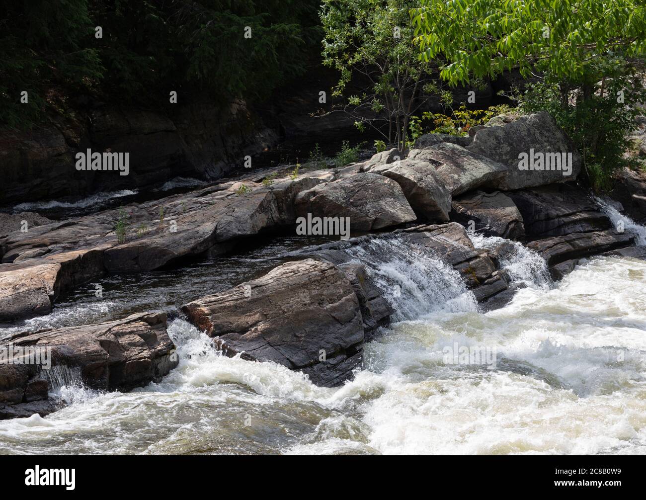 Water spilling over rocks in a river in Northern Ontario in summer ...