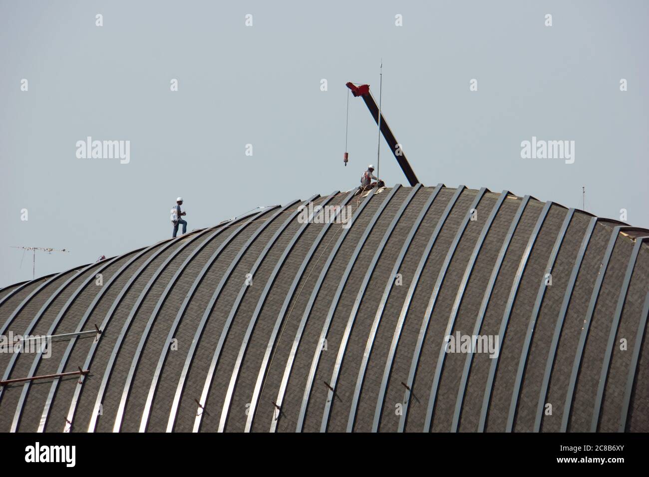 Roof repairing construction workers with crane lifting on a building ...