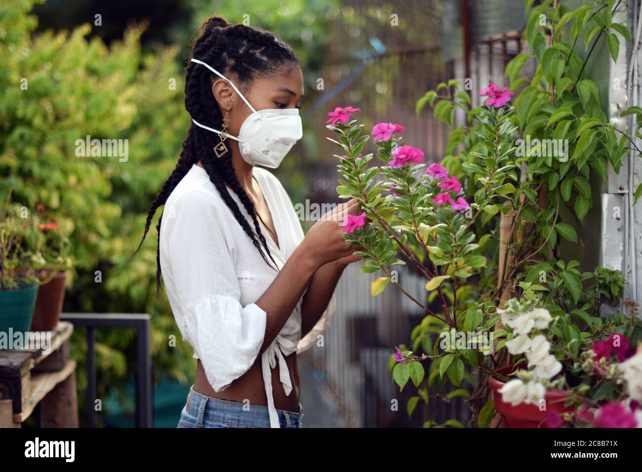 Young woman gardening in face mask Stock Photo - Alamy