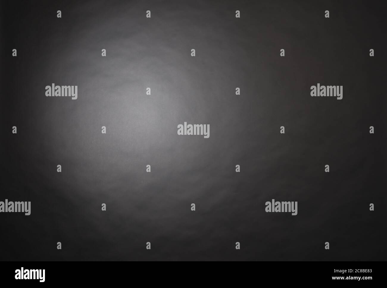 Dark grey studio backdrop lit up by a single light creating a drop off ...