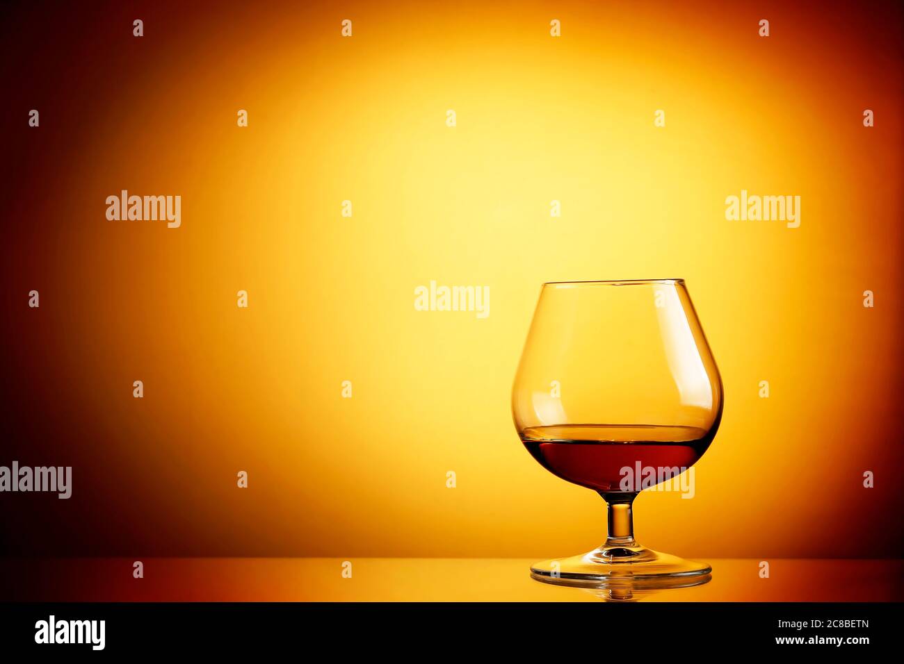 single glass of cognac against orange gradient Stock Photo - Alamy