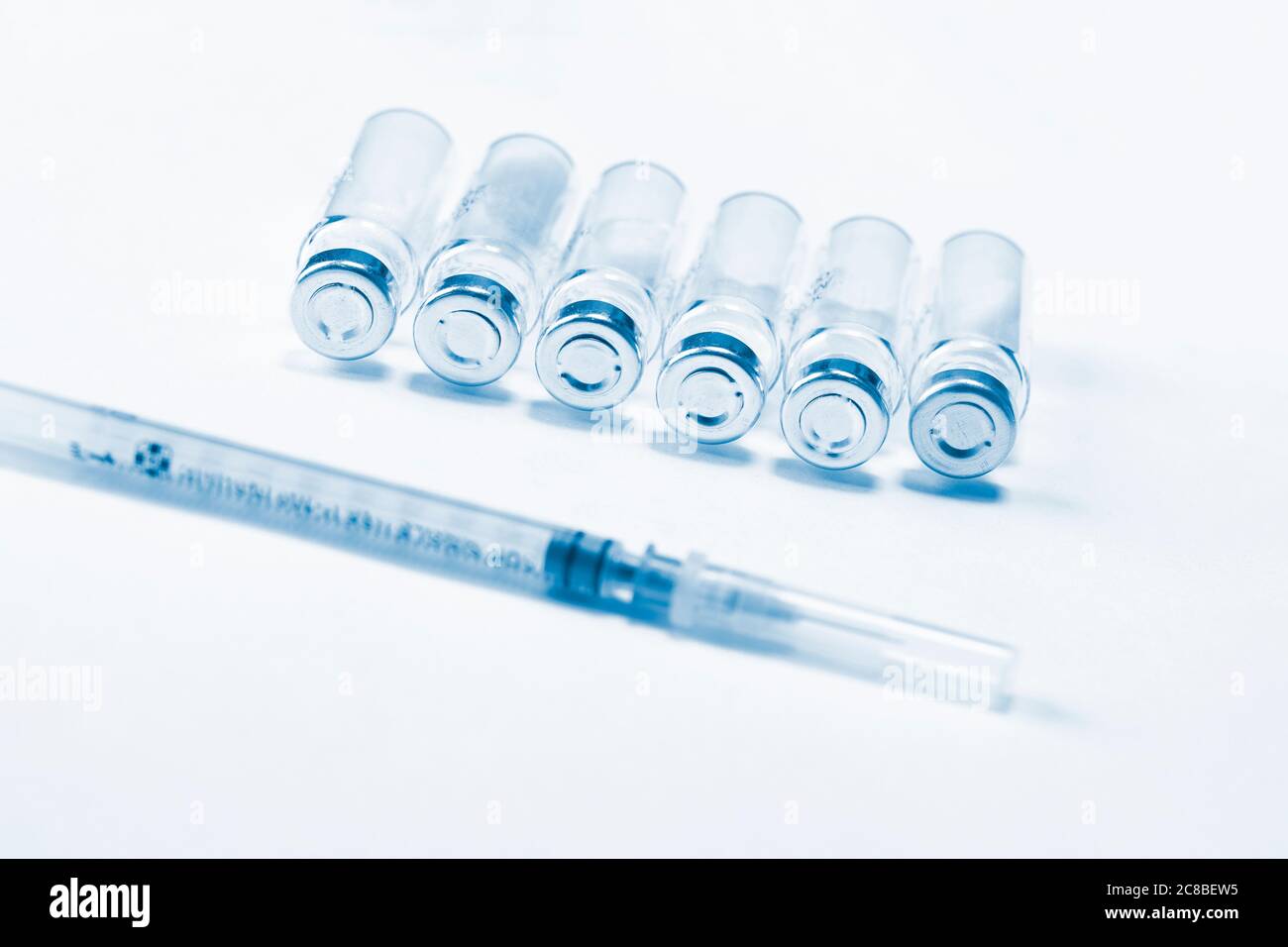 syringe and row of glass vials with medication on white background ...