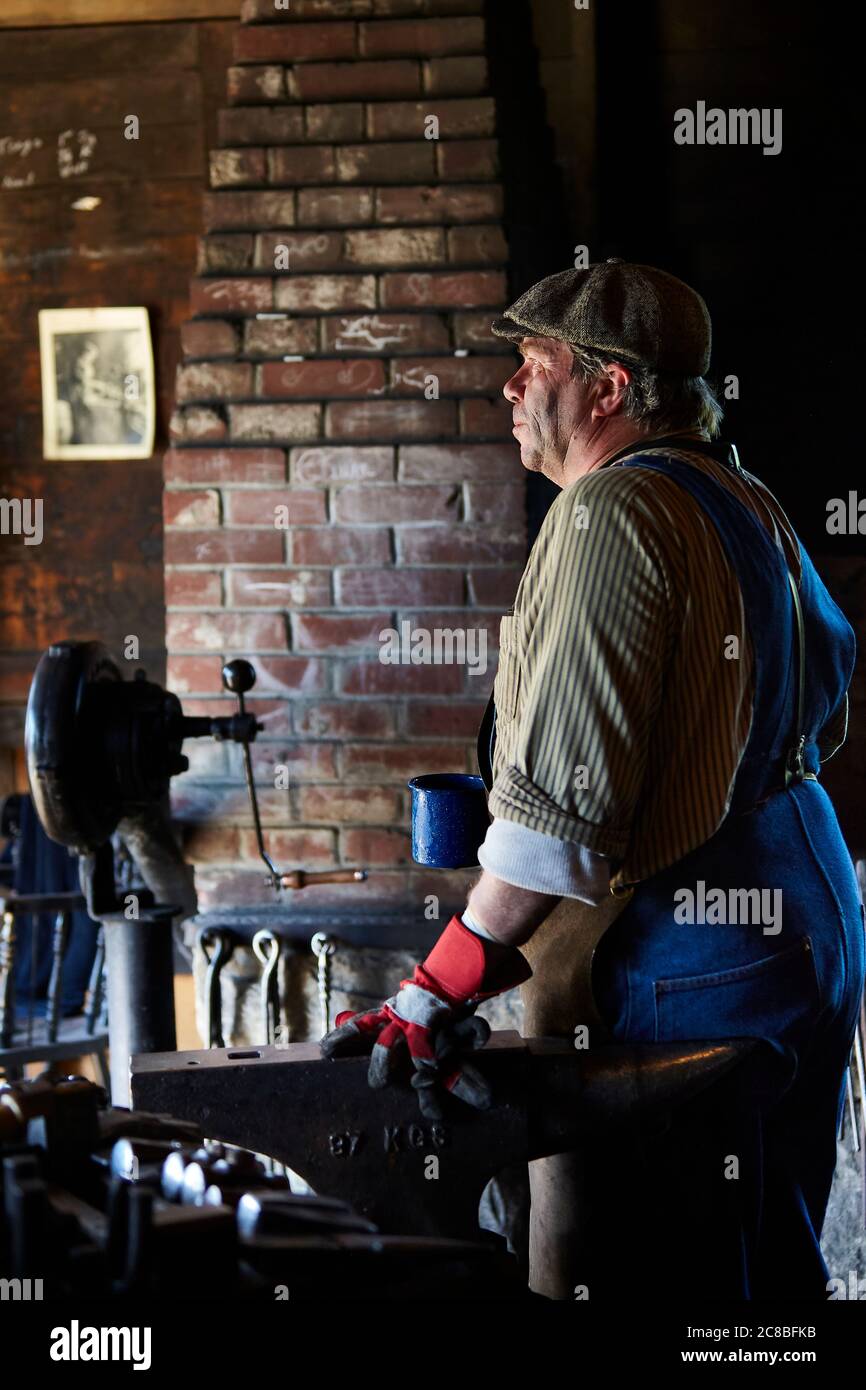 Blacksmith working at a traditional forge inside a historic workshop at ...