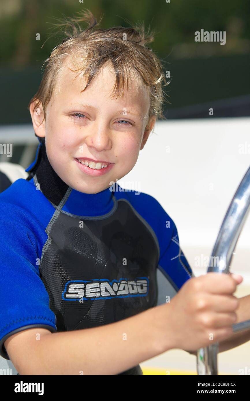 Young boy learning how to drive a boat on Shuswap Lake Stock Photo - Alamy