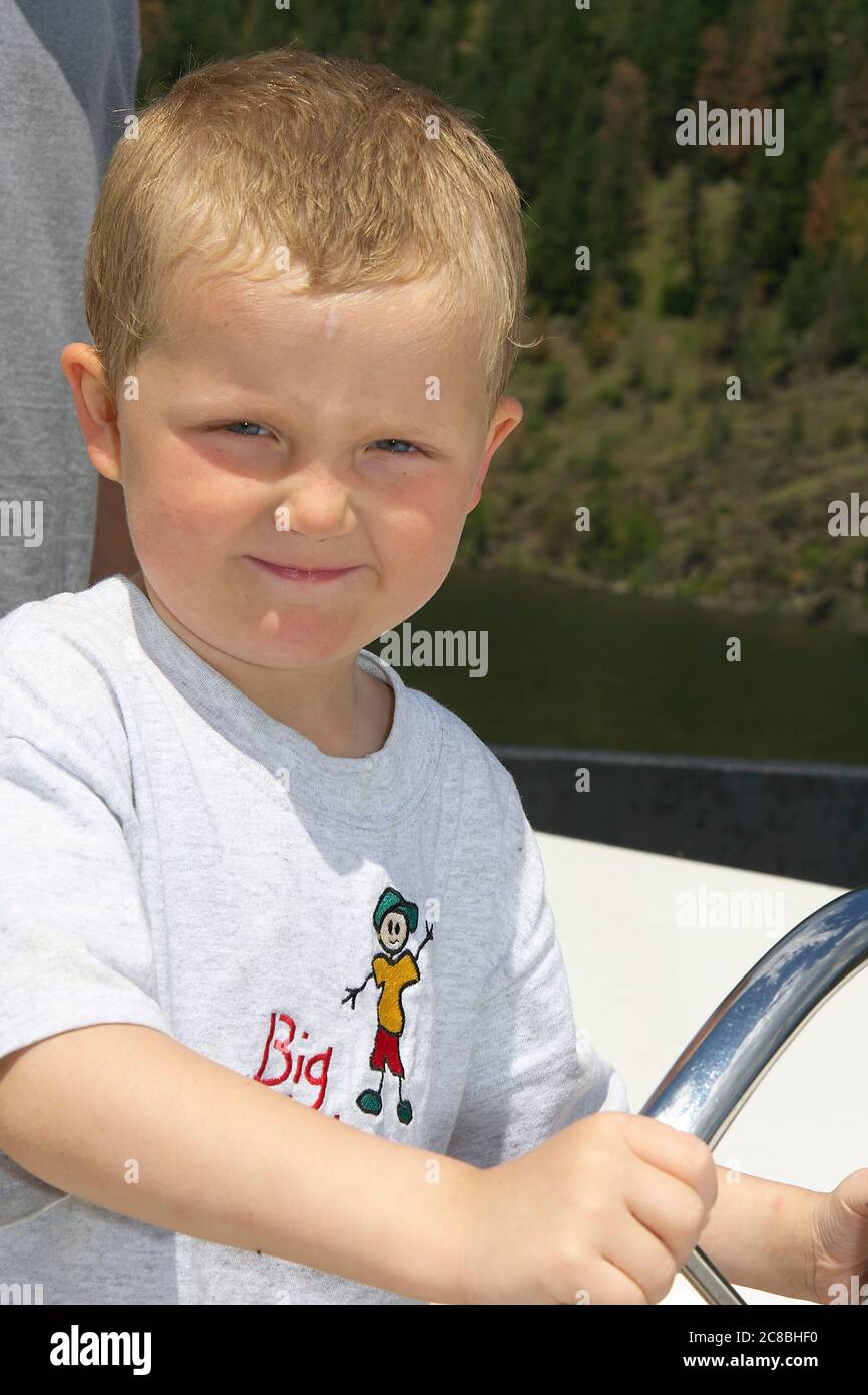 Young boy learning how to drive a boat on Shuswap Lake Stock Photo - Alamy
