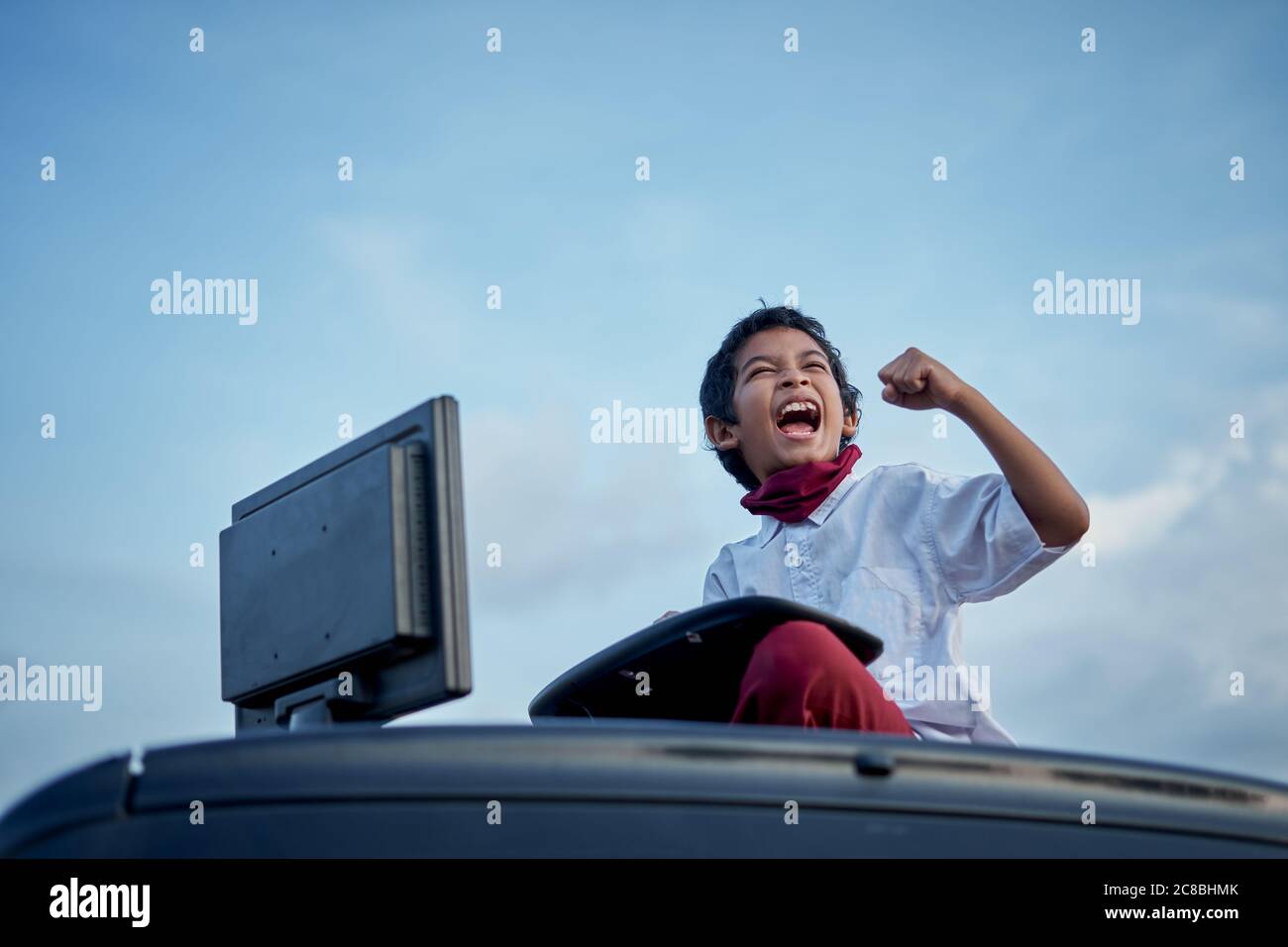 Excited Schoolboy fist pumps while working on a homework using computer ...