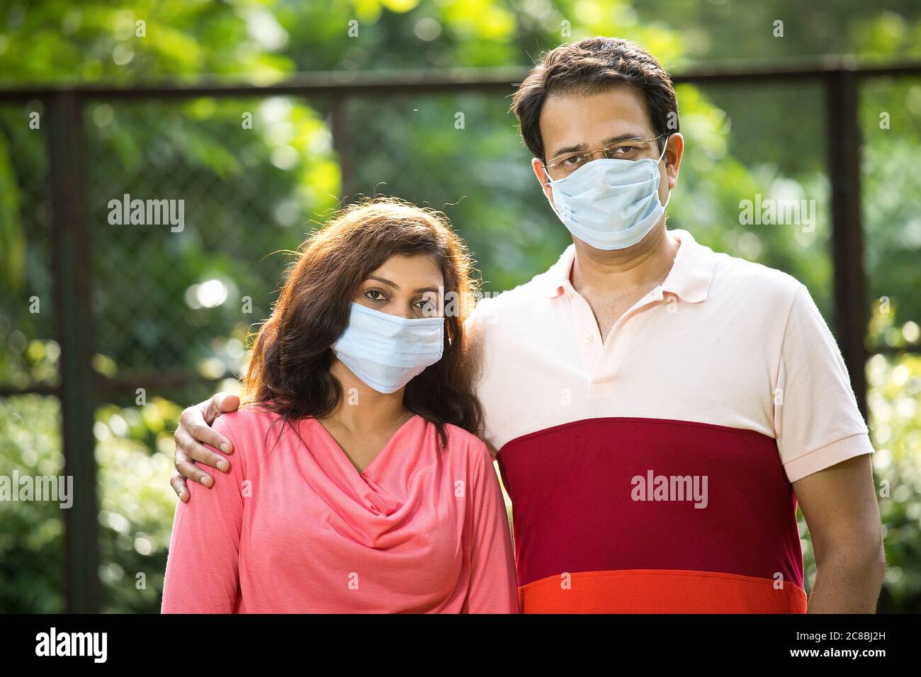 Couple with protective face mask at park Stock Photo - Alamy