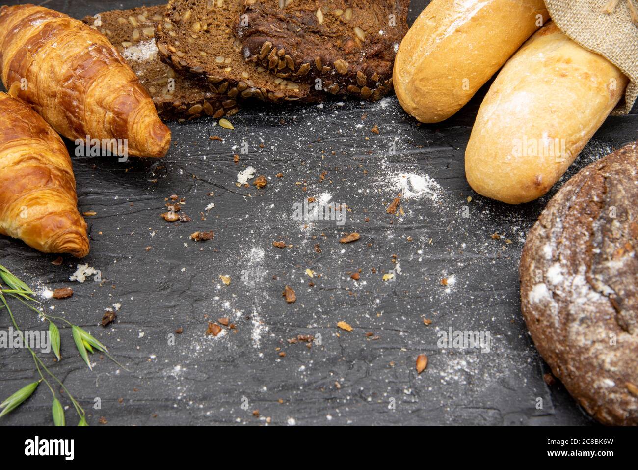 Frame made of different bread and white flour on a dark slate ...