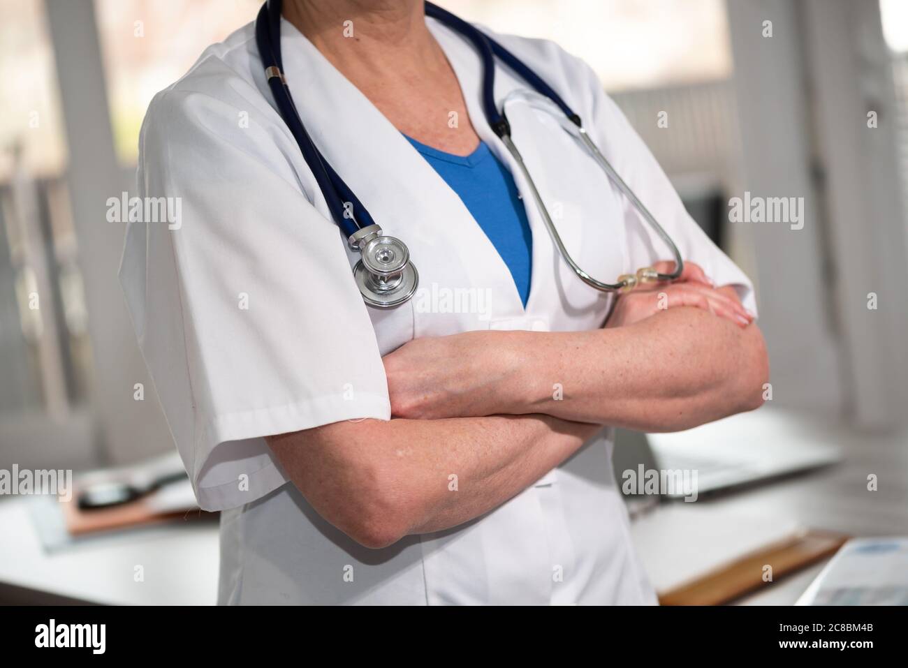 Female doctor with arms crossed in medical office Stock Photo - Alamy