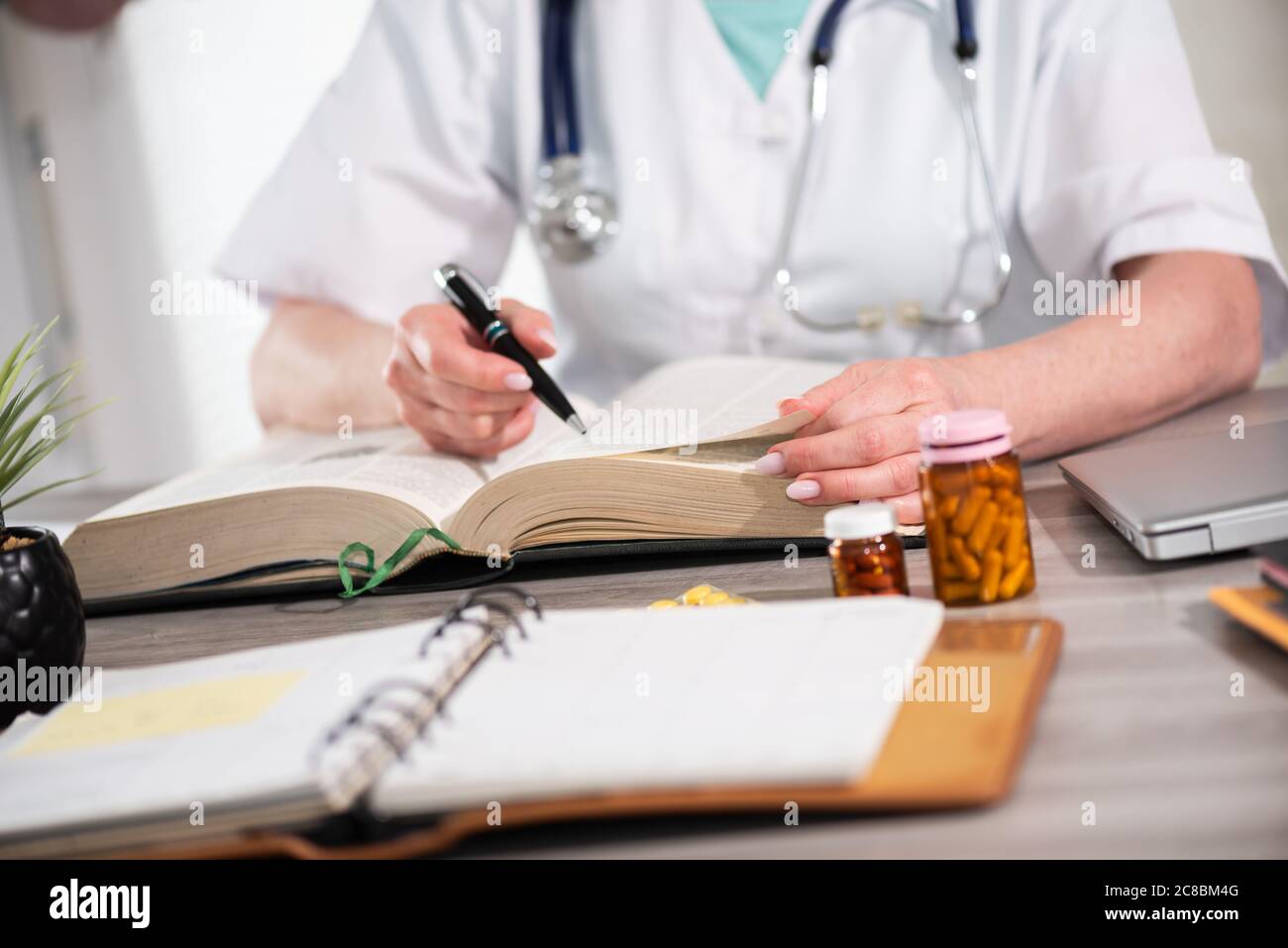 Female doctor reading a textbook in medical office Stock Photo - Alamy
