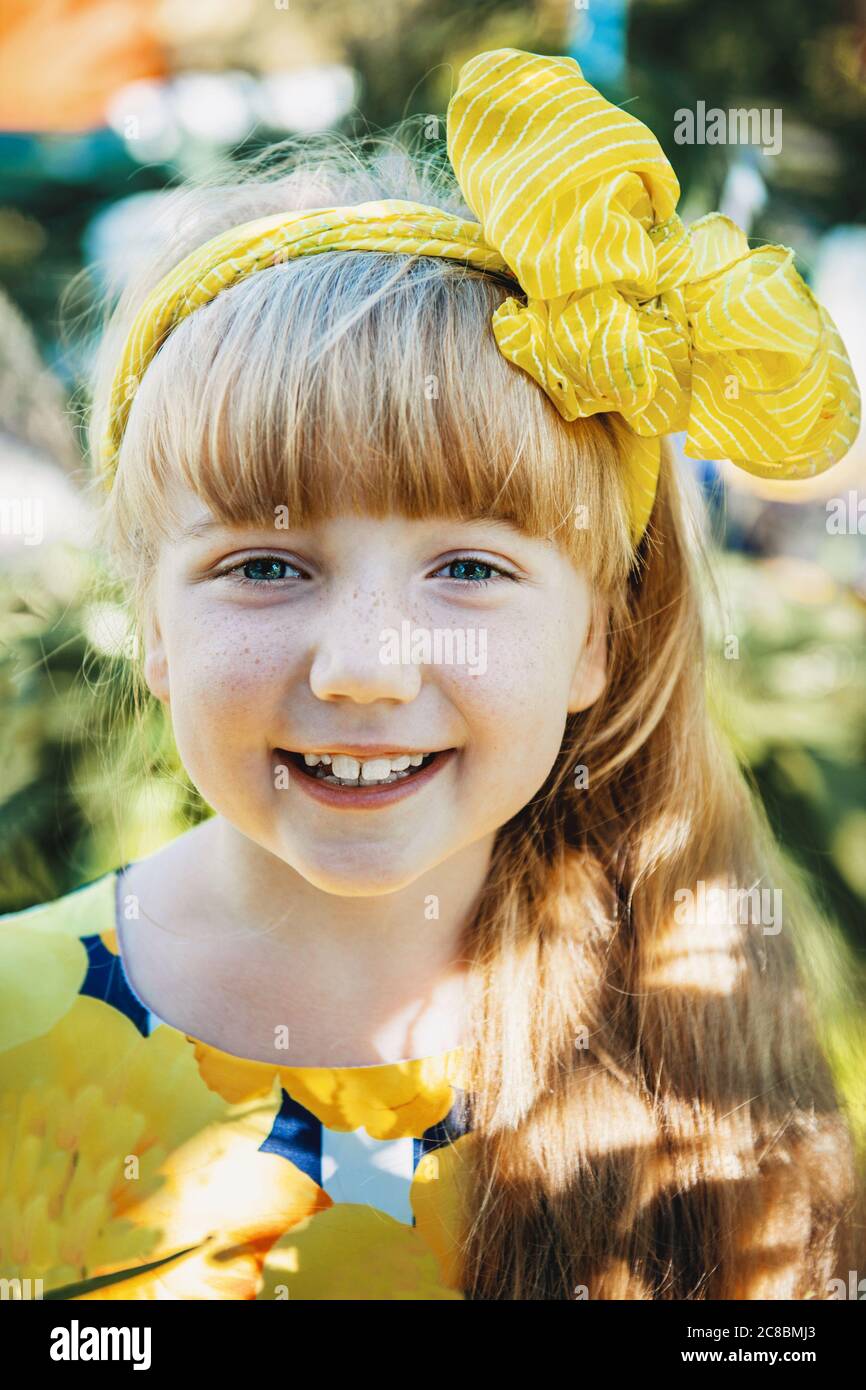 beautiful little girl with long Golden hair and a yellow bow looks at ...