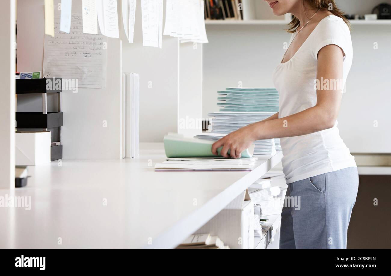 Office worker holding sorting paper materials standing in office Stock ...