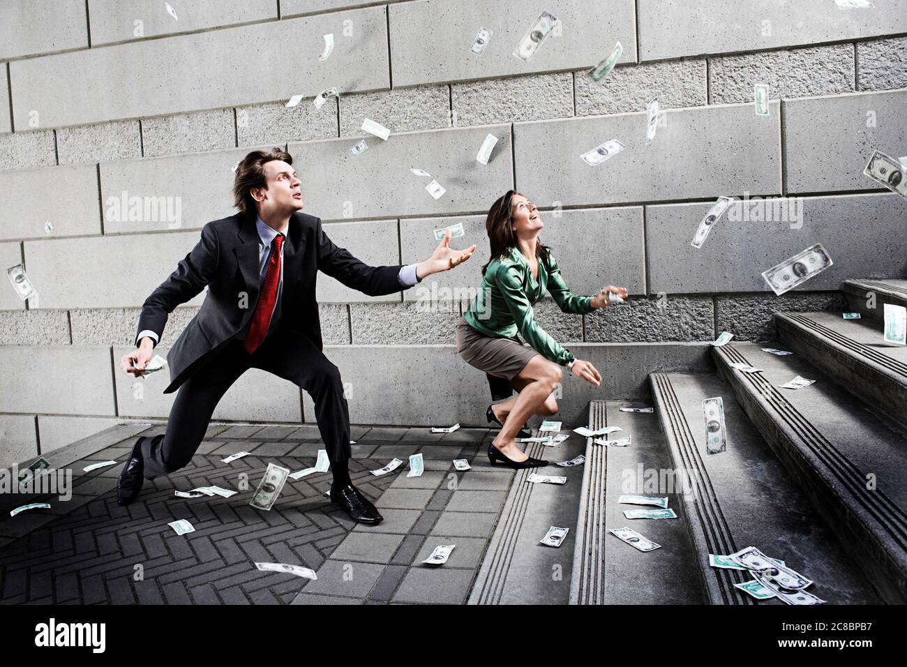 Businessman and woman catching falling money on steps Stock Photo - Alamy