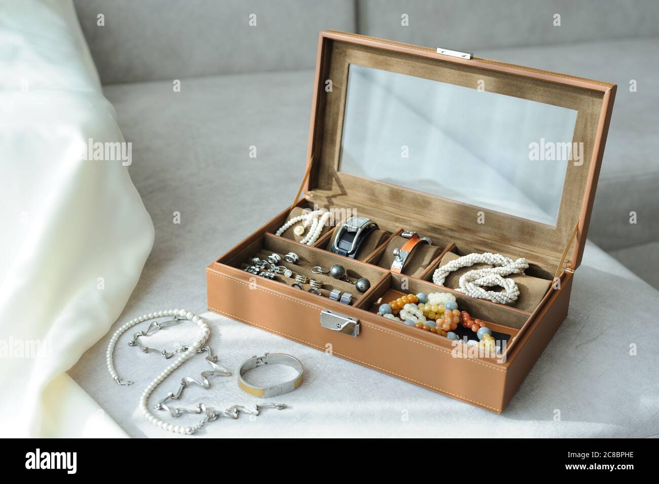 Leather jewelry box with jewelry and accessories laid on a couch with ...