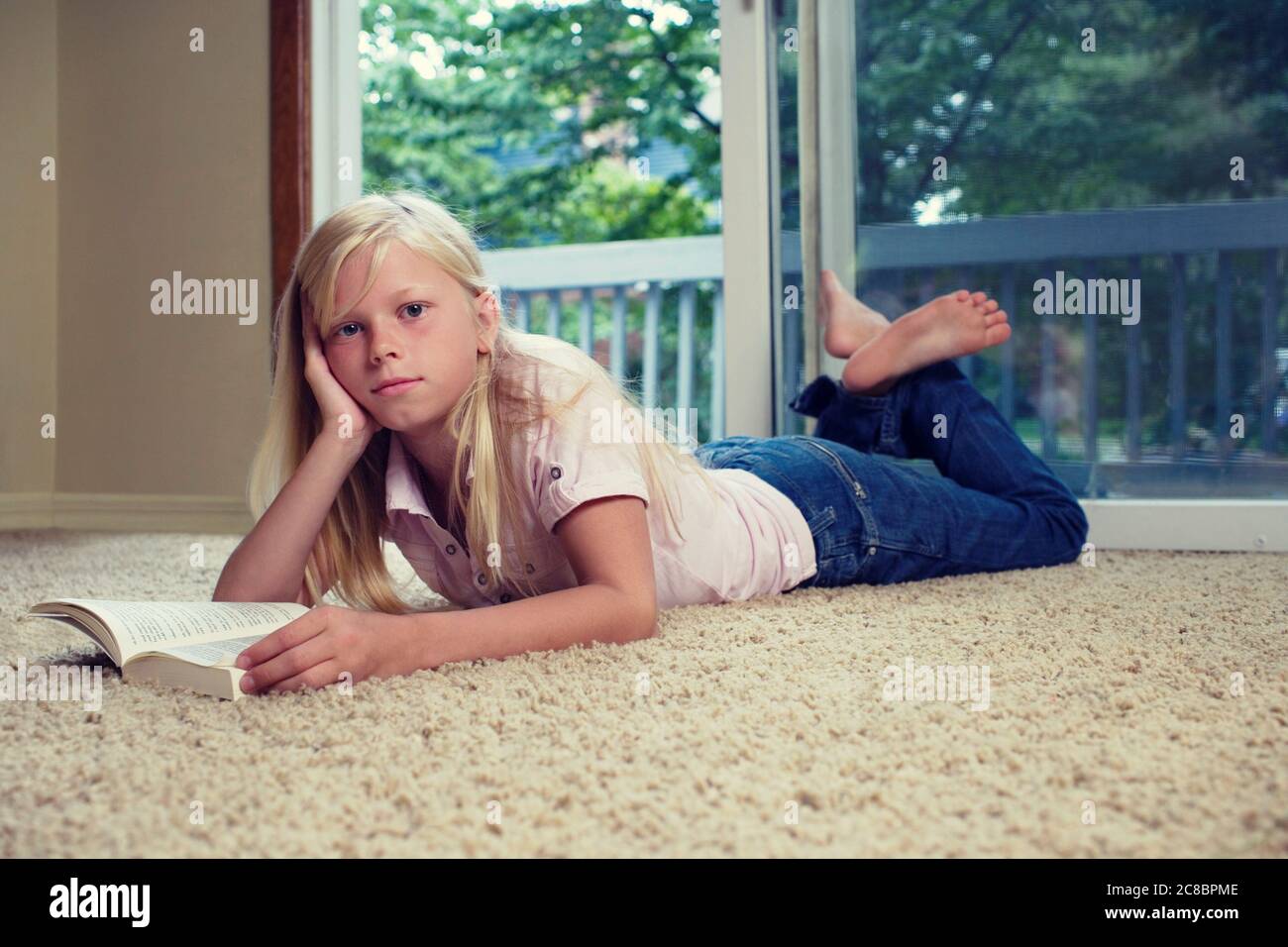 Girl lying on carpet, reading book Stock Photo - Alamy