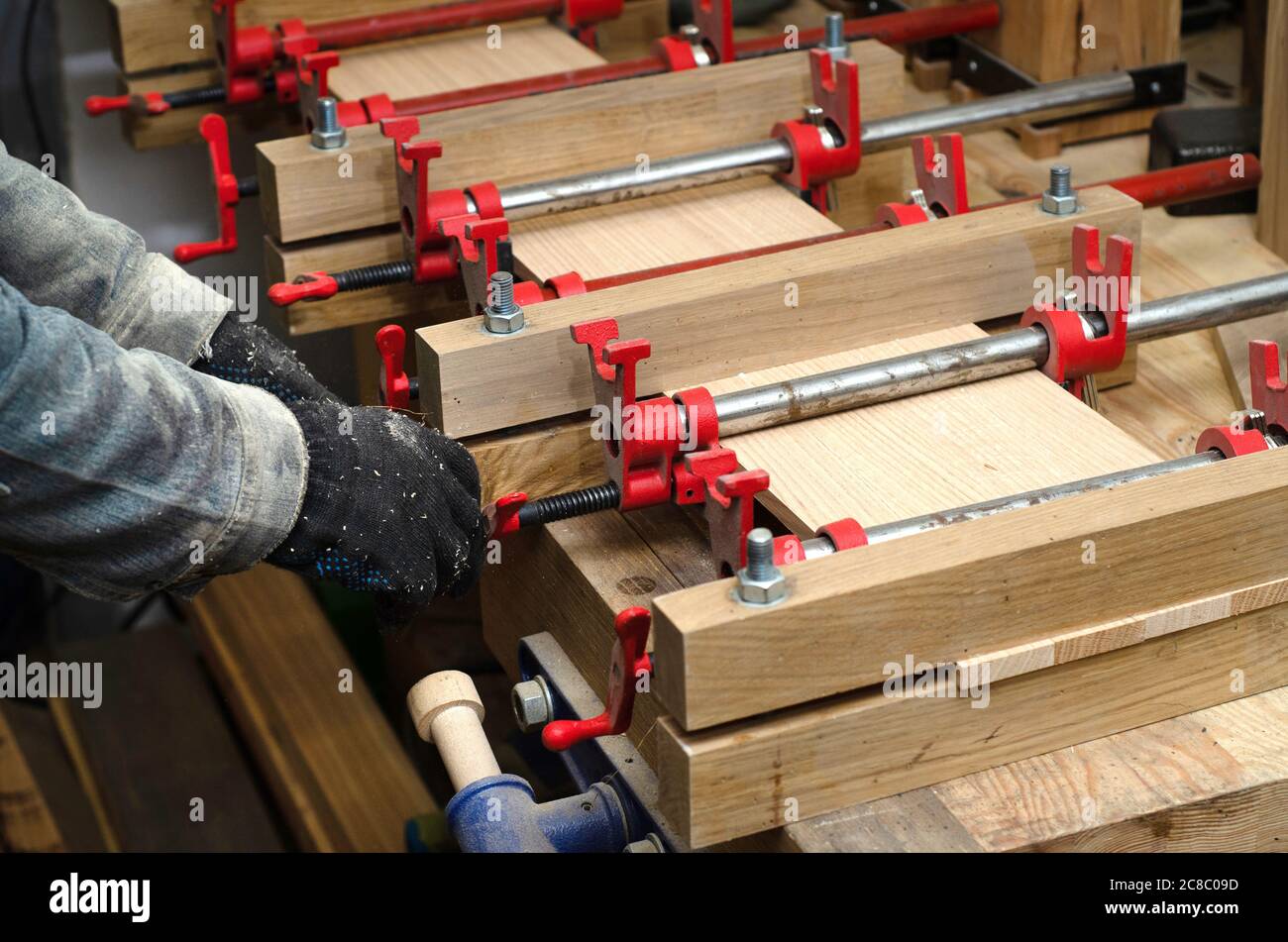 Red joiner's clamps are fixed on product, gluing of boards. Bonding of ...