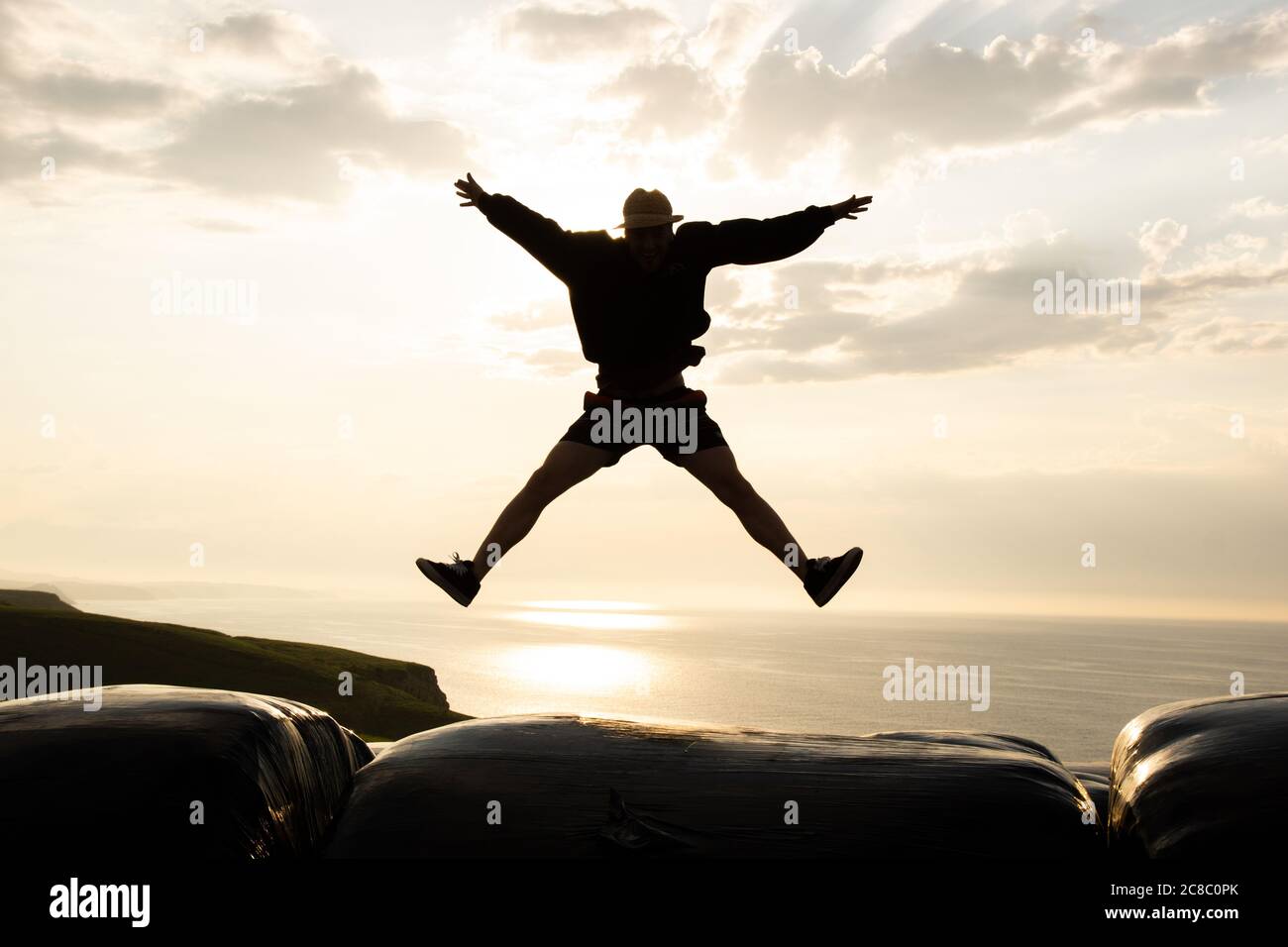 Young man jumping happy with the sunset behind him Stock Photo - Alamy