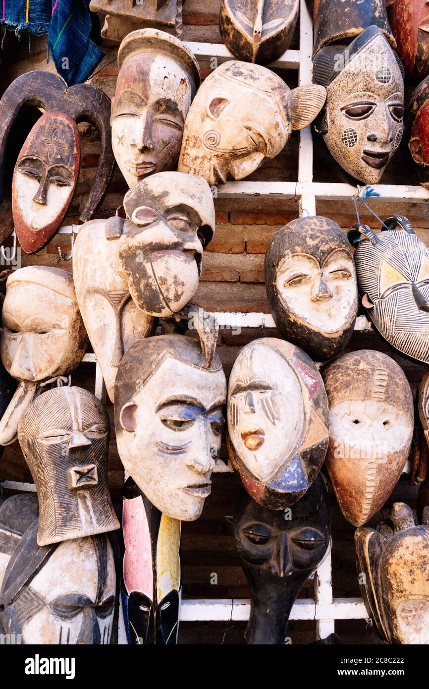Vertical photo of some wooden masks hanging in a shop in a market in ...