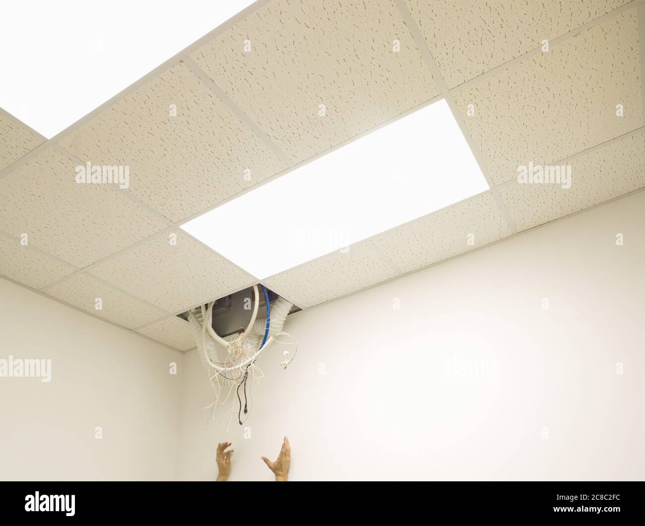 Hands reaching towards cable hanging from hole in ceiling Stock Photo ...